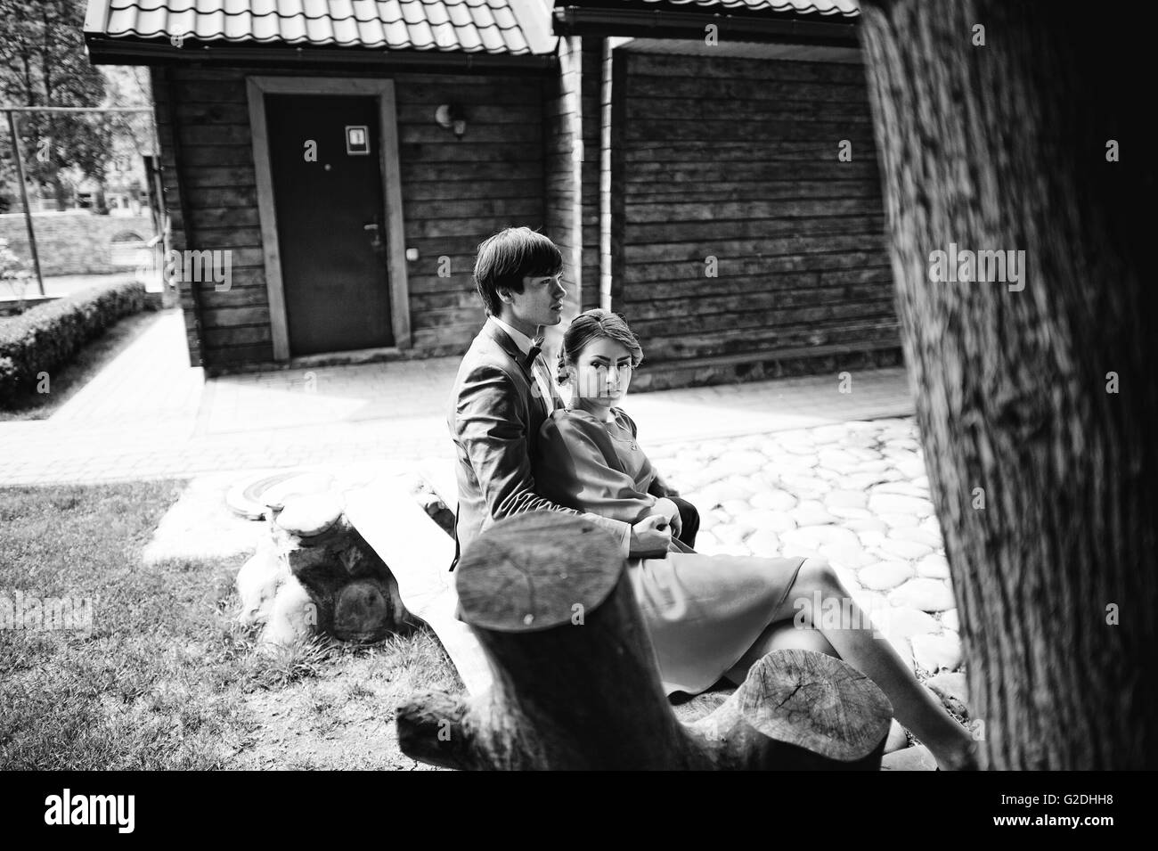 Couple sitting on bench. Stylish man at velvet jacket and girl in red ...
