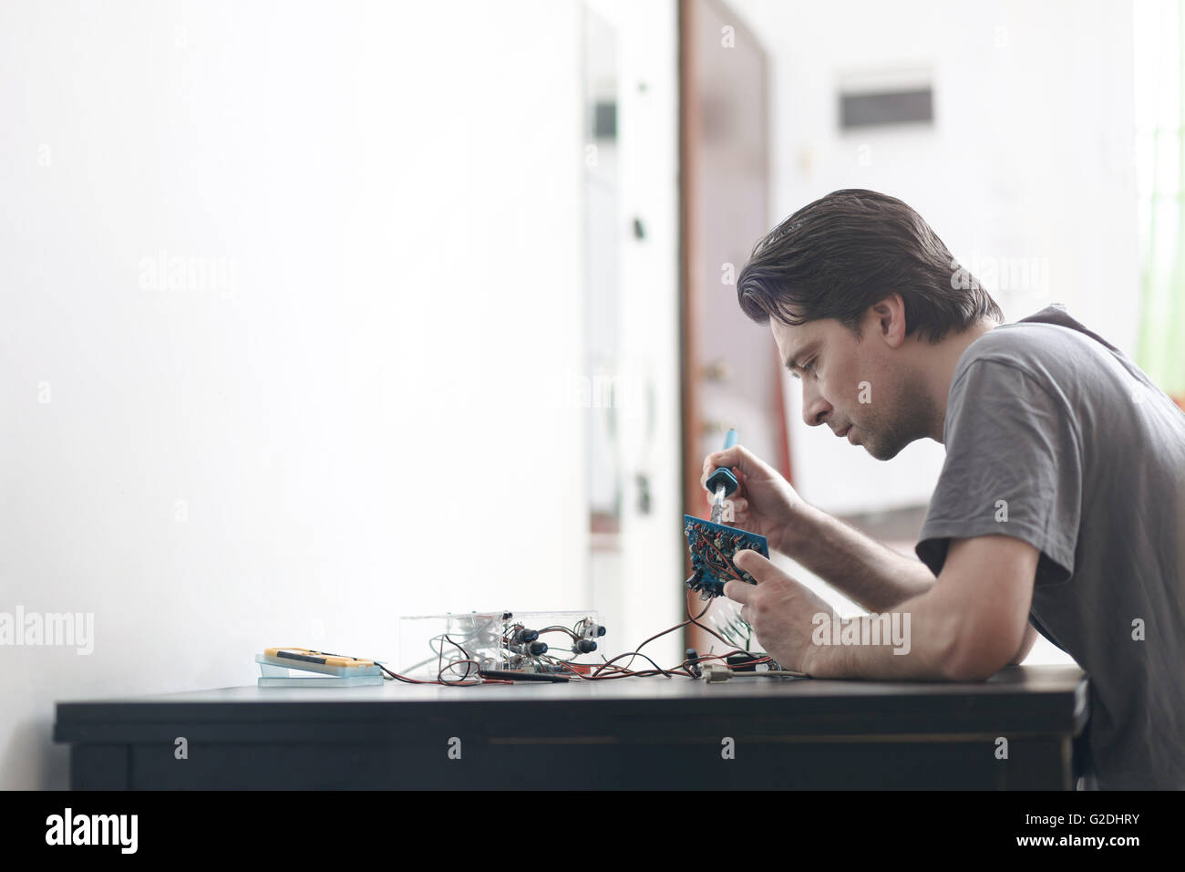 Young man making an electronic device soldering and adjusting the ...