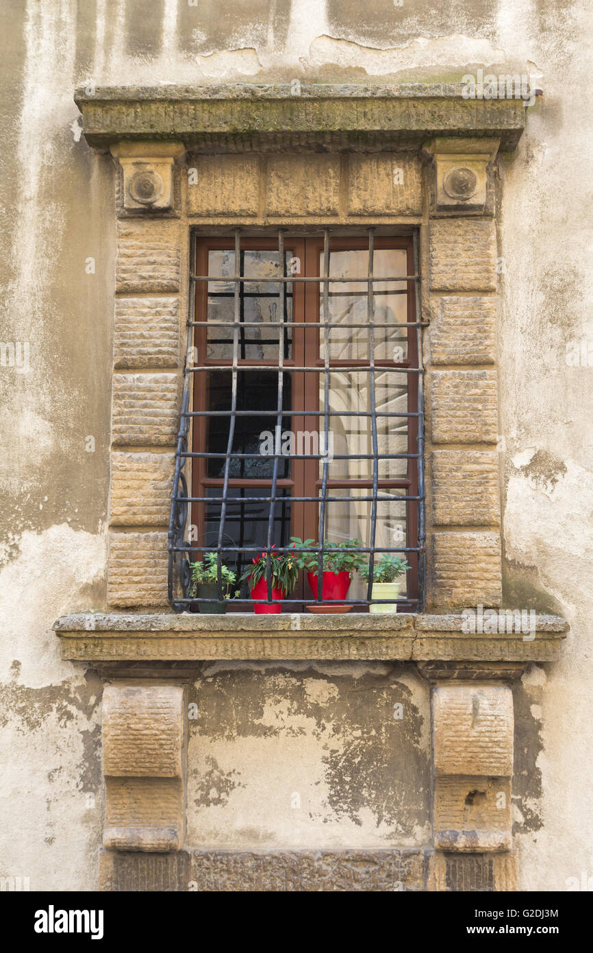 Medieval window with its solid metal grates and pots with flowers Stock ...