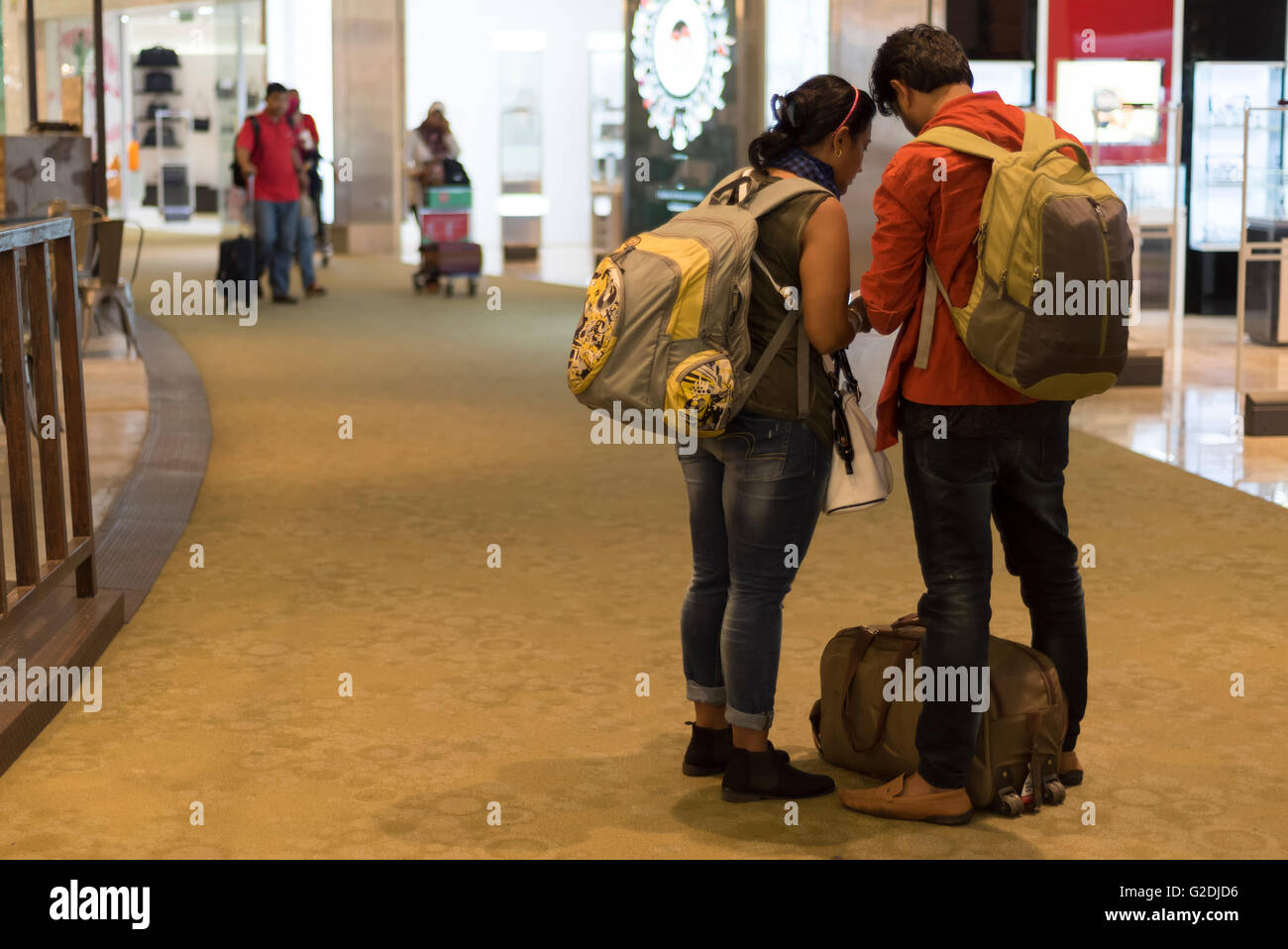 Two tourist sarching for location at airport Stock Photo - Alamy