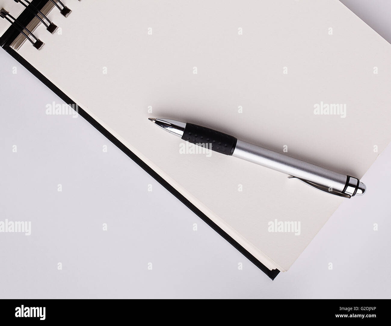 Metal ballpoint pen resting on an opened blank white notepad with ...
