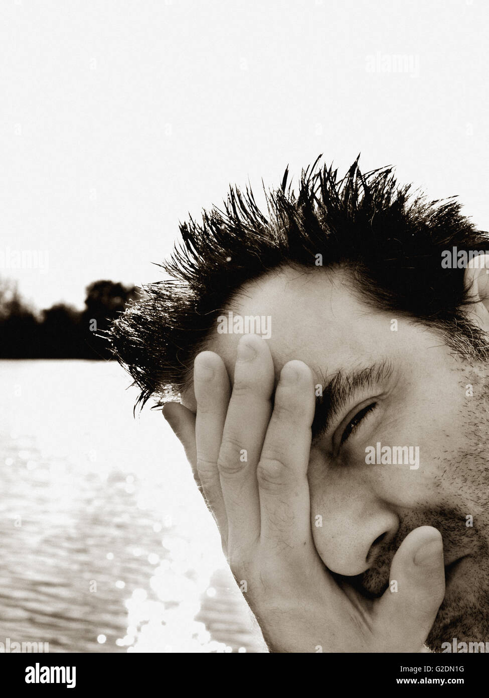 Man with Hand on Face by Lake Stock Photo - Alamy