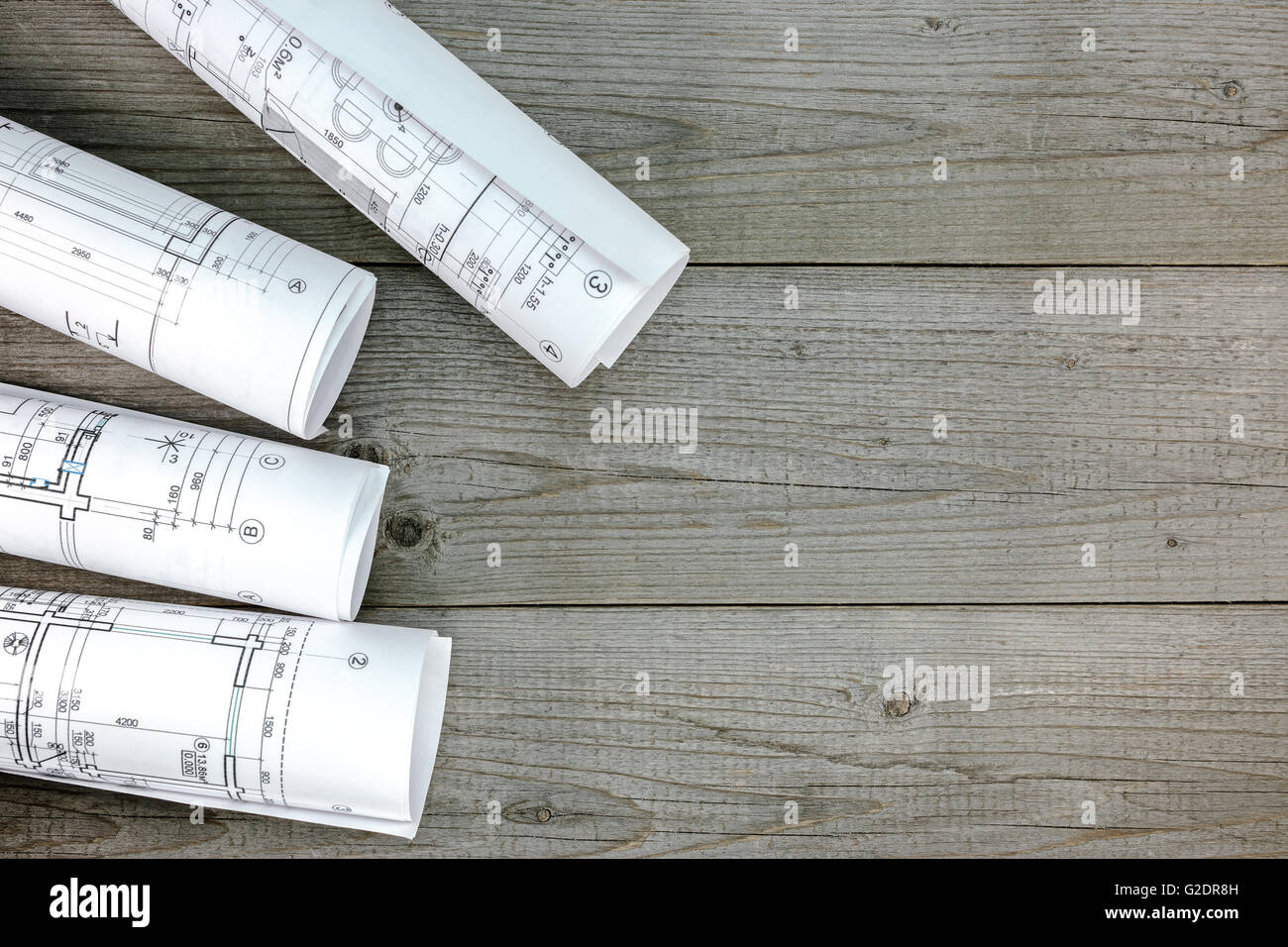 rolls of architectural blueprints and house plans on gray wooden table ...