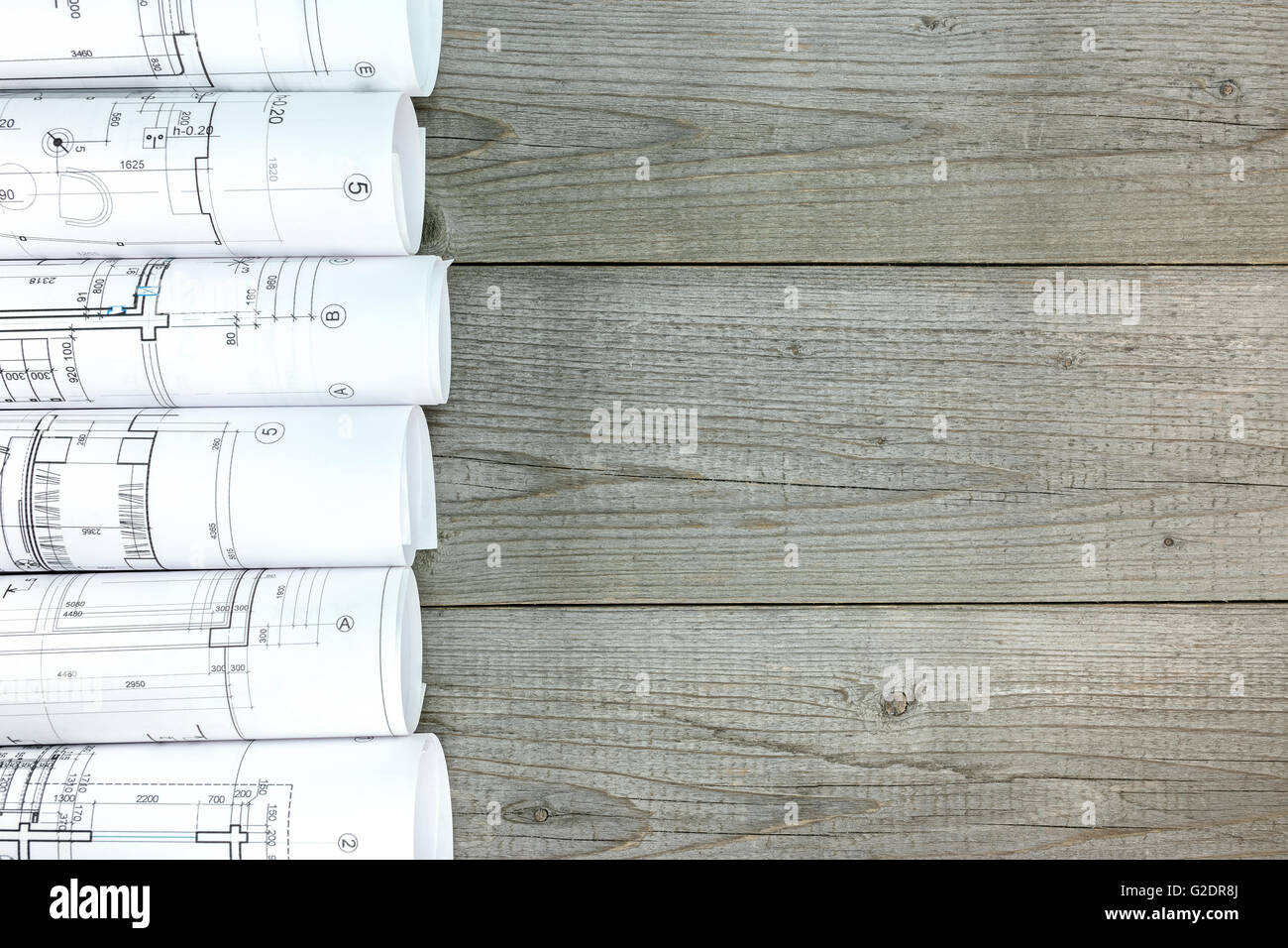 rolls of architectural blueprints and house plans on gray wooden table ...