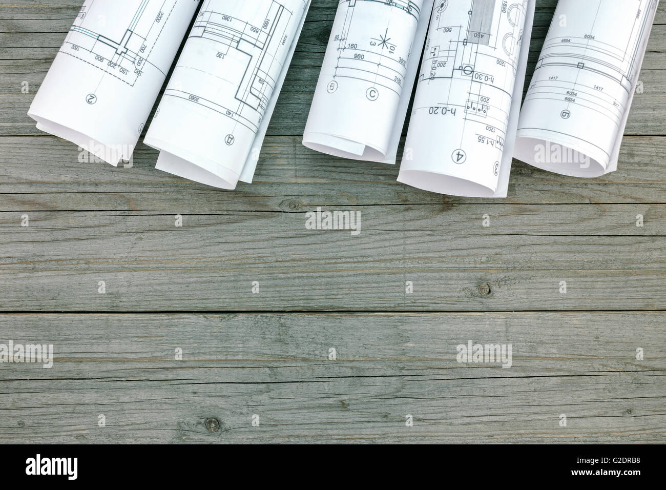 rolls of architectural blueprints and house plans on gray wooden table ...