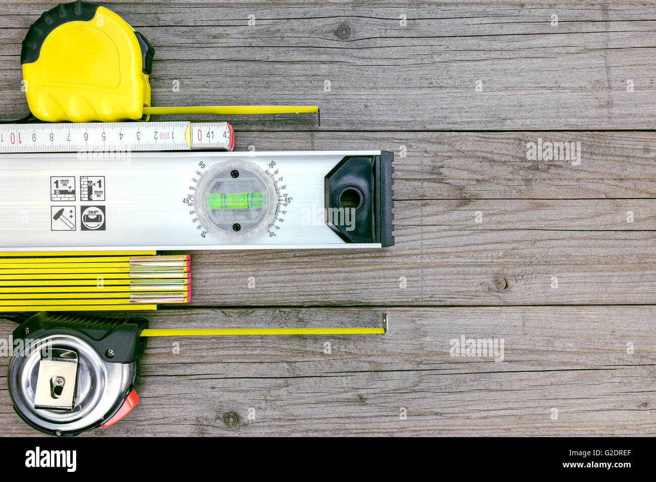spirit level with tape measure and folding rule on gray wooden table ...