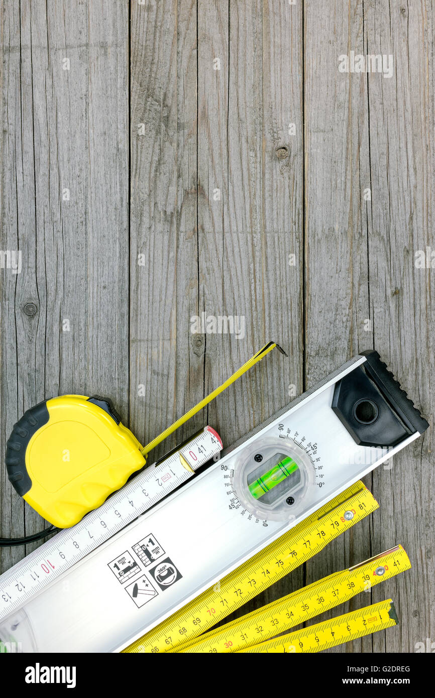 spirit level with tape measure and folding rule on gray wooden table ...