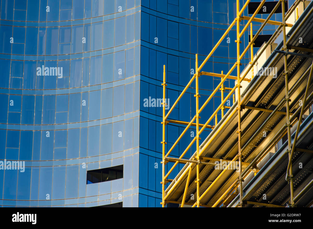 Scaffolding on a building site with a multi story glass tower building ...