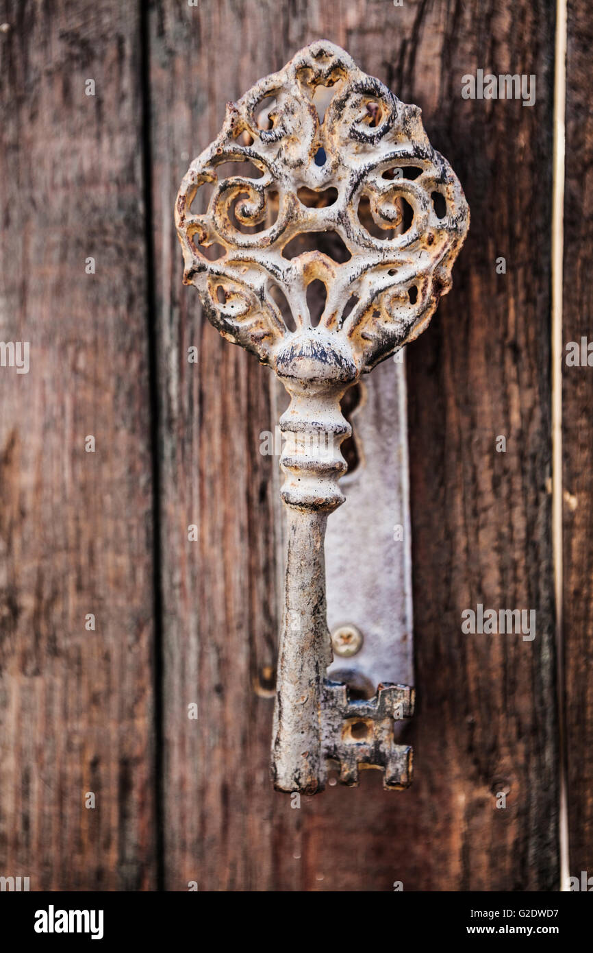 Old rusty key shaped door handle mounted on wood door Stock Photo - Alamy