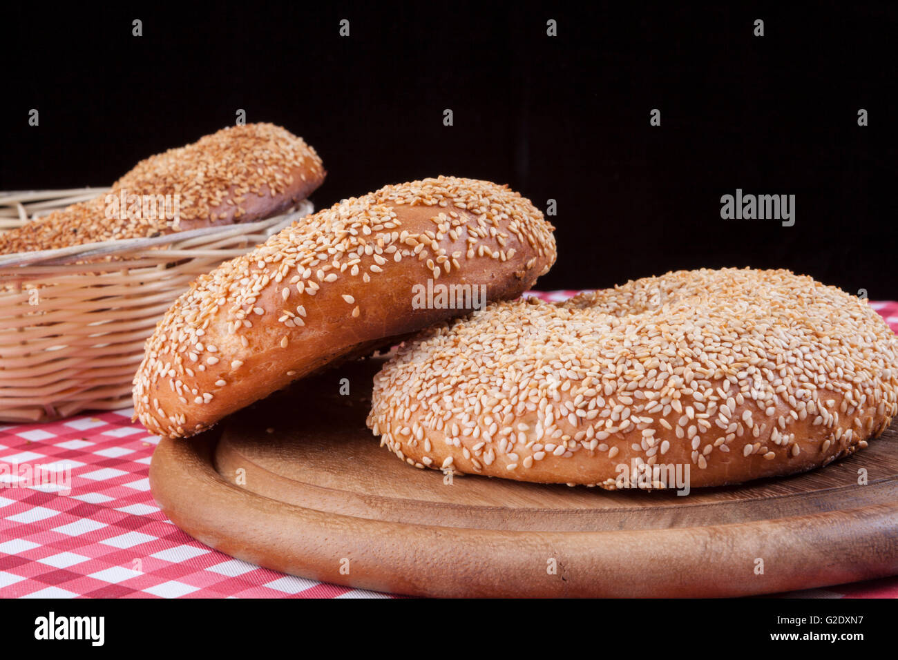 Round Sesame Bagels in basket on red table and black background Stock ...