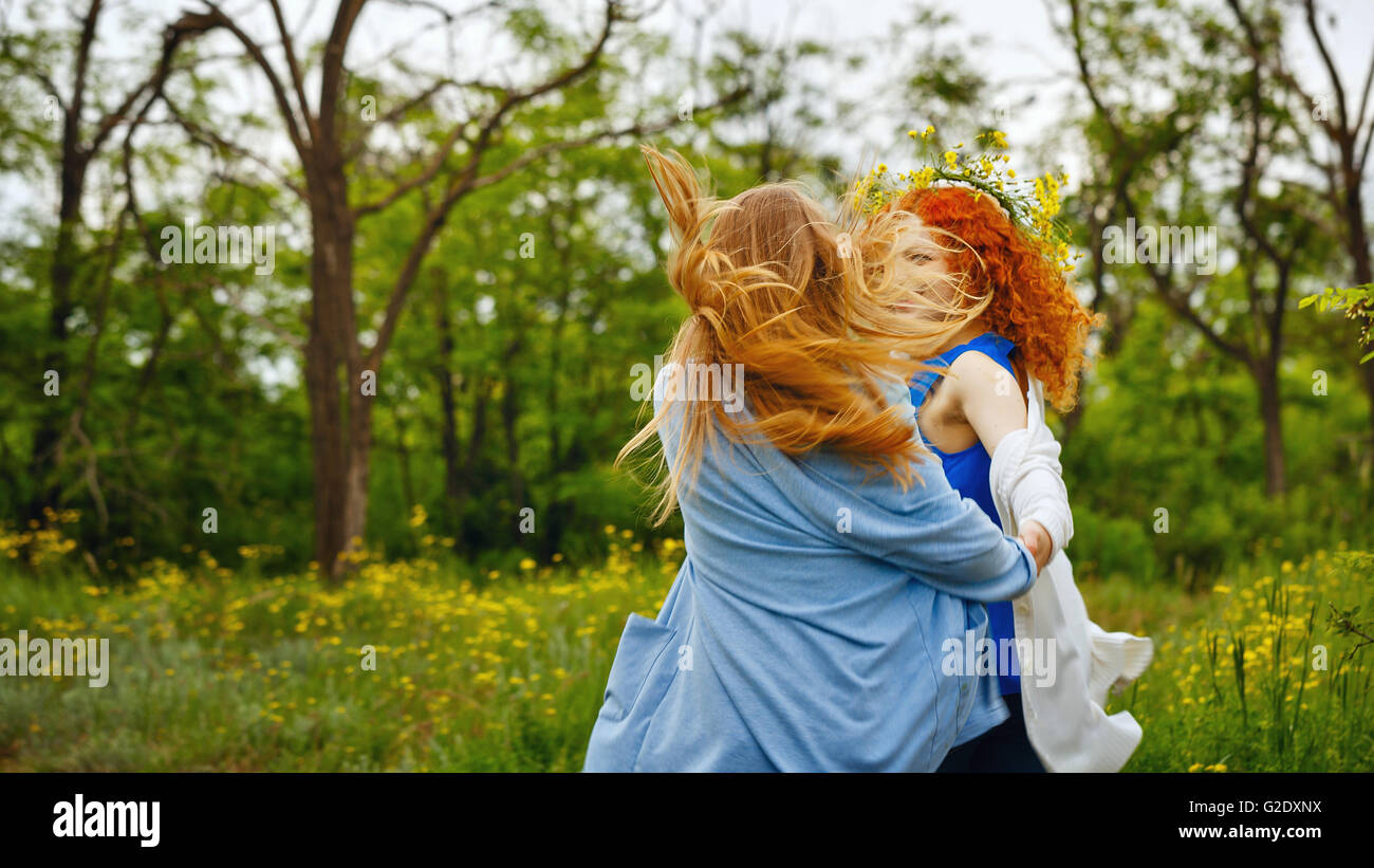 Best friends forever. Girlfriends running away holding hands in a park ...