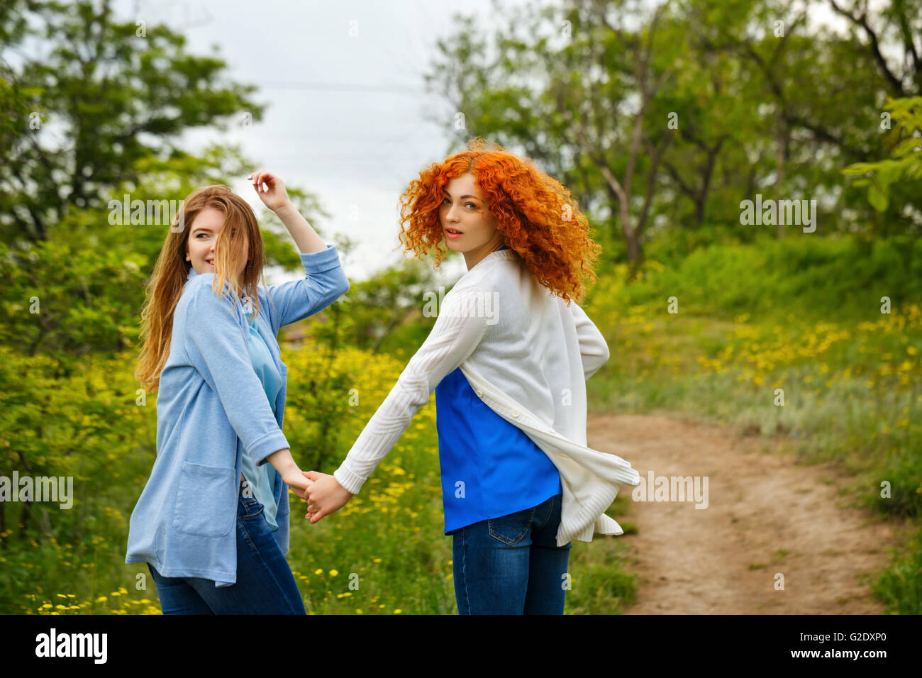 Best friends forever. Girlfriends strolling hand in hand in the park ...