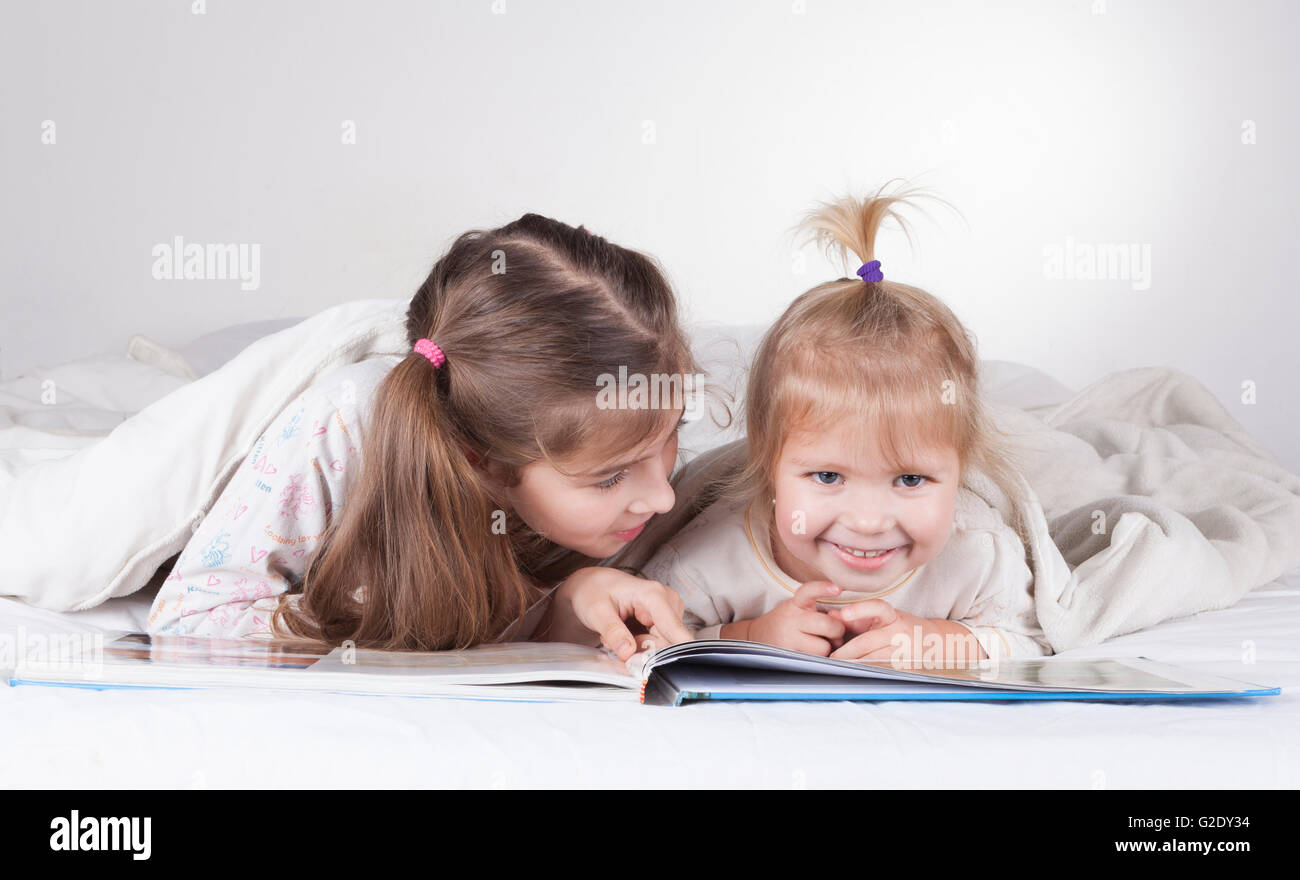 Two sisters reading bad time story in bad with white sheets Stock Photo ...
