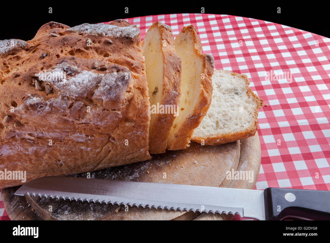Sliced bread on round wood plate and red table with black on the ...
