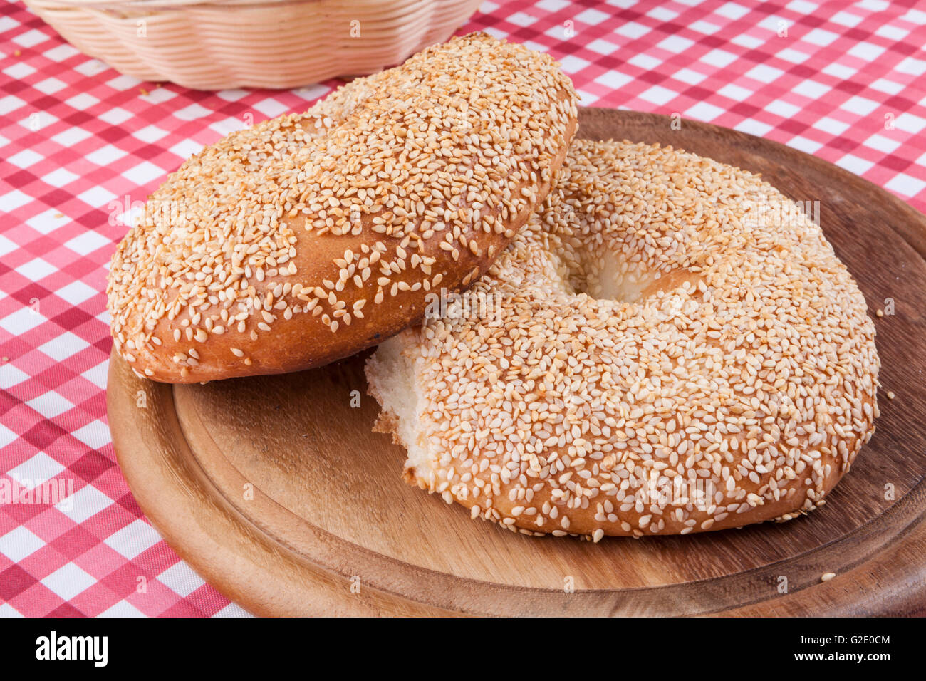 Sesame round bagels on round wood plate on red table Stock Photo - Alamy