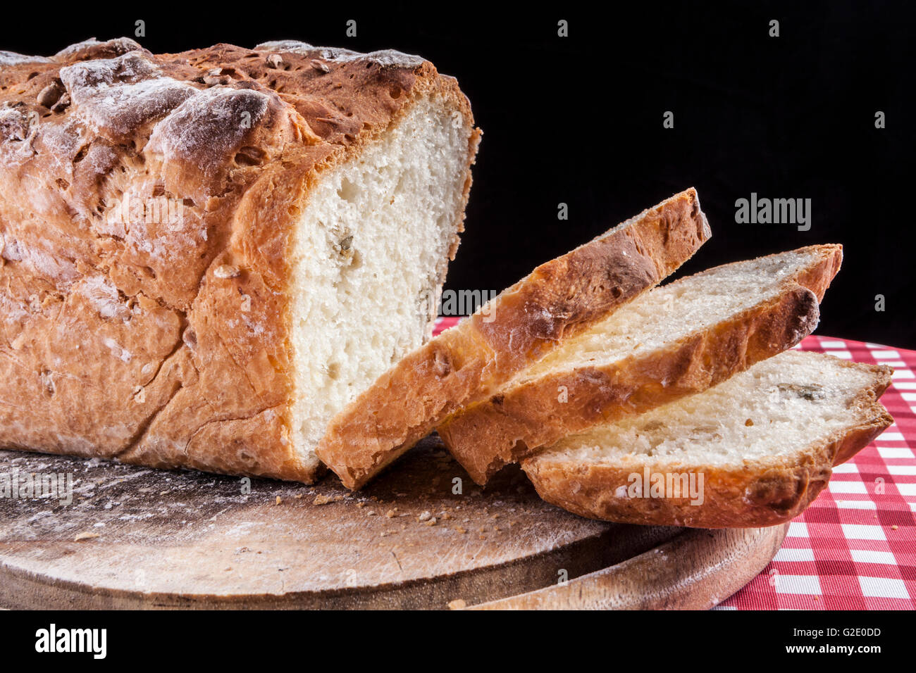 Sliced bread round wood plate and red table with black on the ...