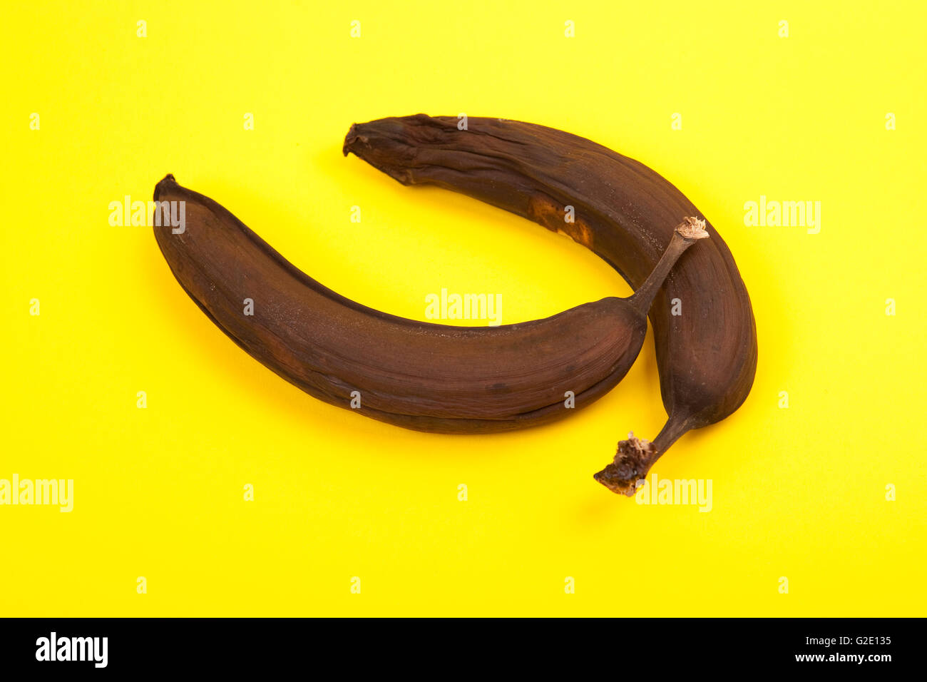two black rotten bananas on yellow background Stock Photo - Alamy