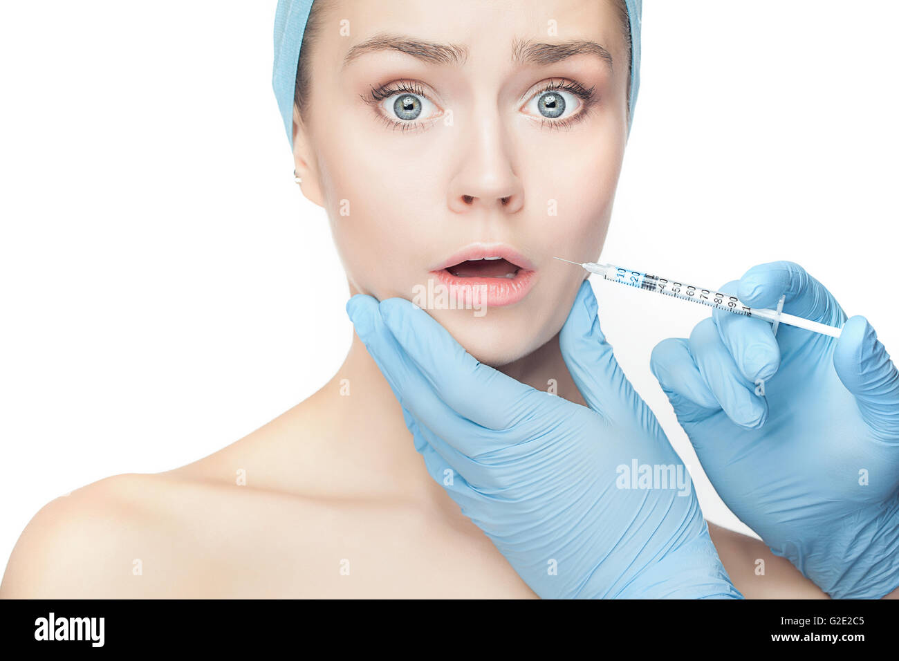 Attractive surprised and scared woman at plastic surgery with syringe ...