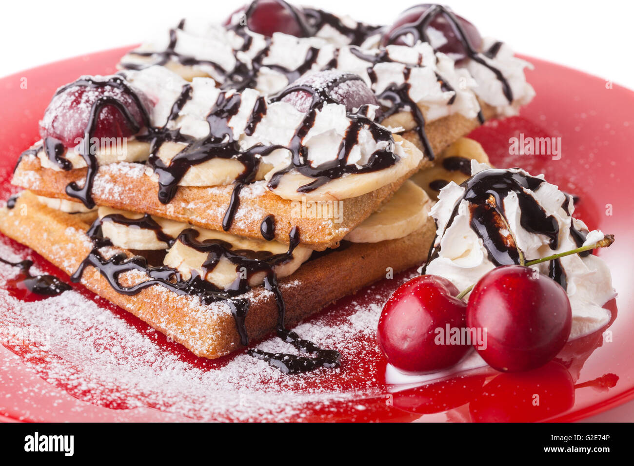 Belgian Waffle With Chocolate Syrup Whipped Cream And Red Cherry On Red
