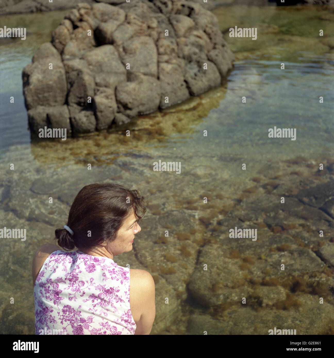 Woman Sitting by Water, Rear View Stock Photo - Alamy