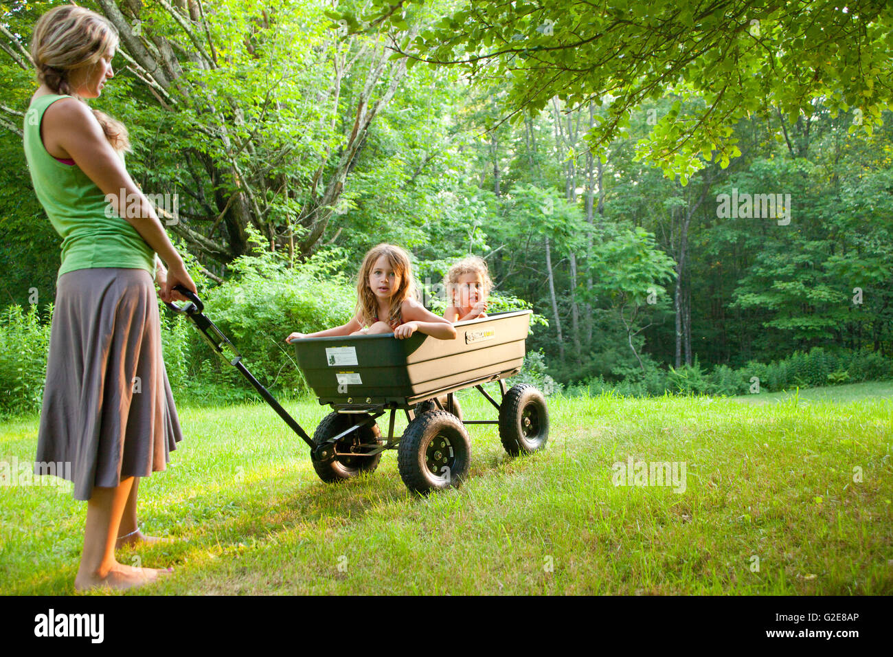 Woman Pulling Two Children in Wagon in Yard Stock Photo - Alamy