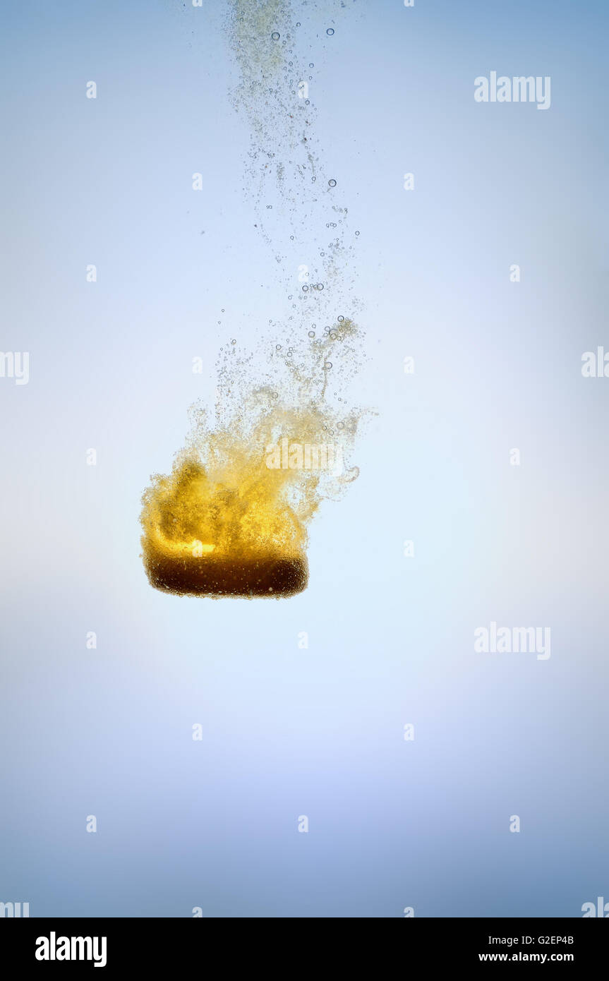 Effervescent orange tablet falling blue isolated Stock Photo - Alamy