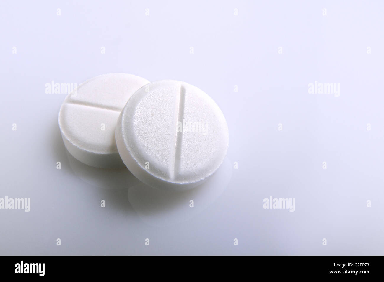 two round white pills on a glass table Stock Photo - Alamy