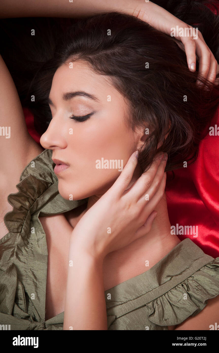 Beautiful young woman laying down on red silk hands touching neck Stock ...