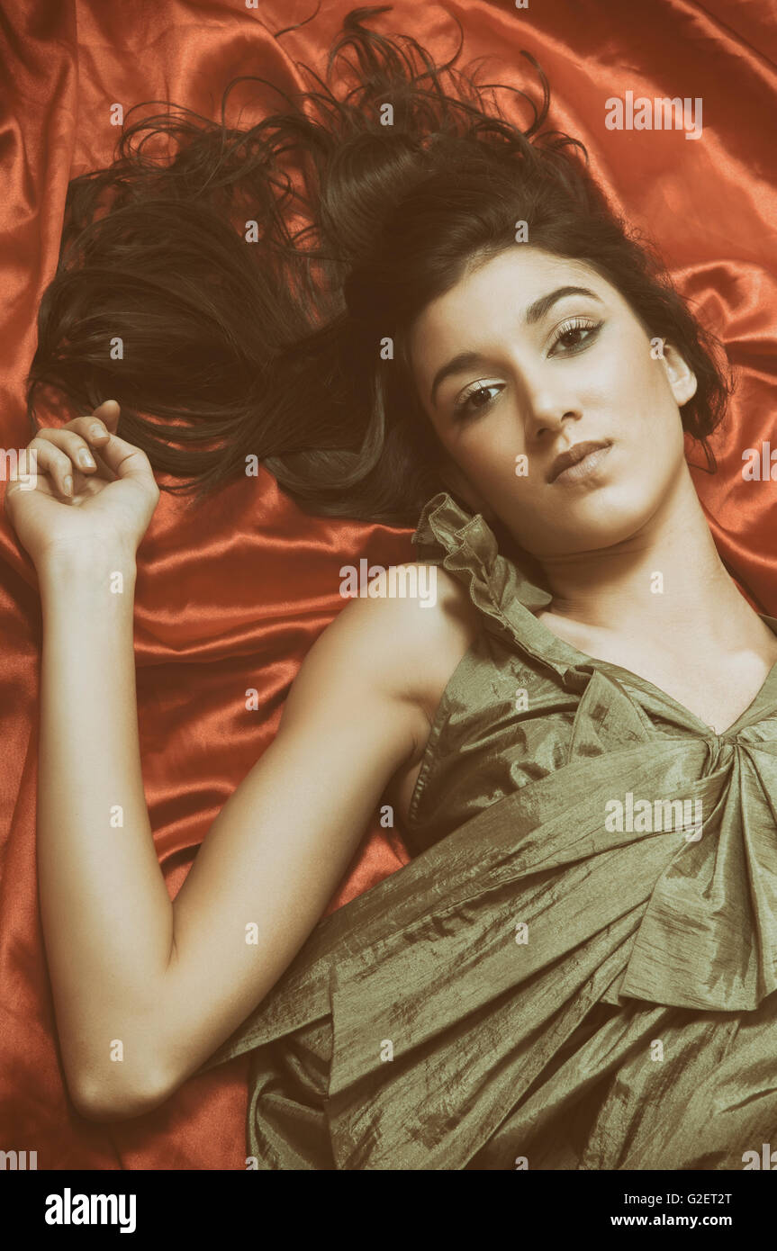 Sad young woman laying down on red silk Stock Photo - Alamy