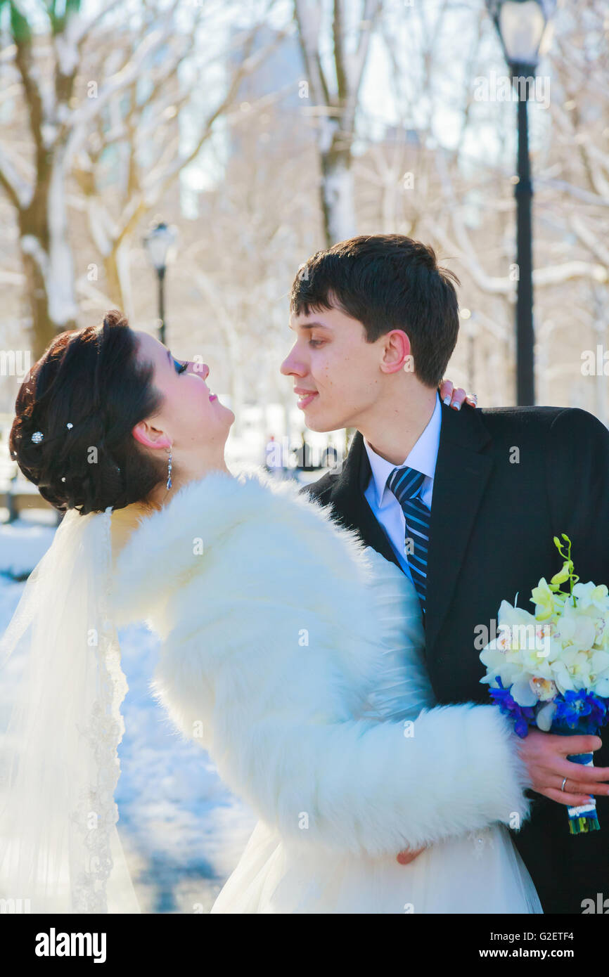 Young couple newlyweds walking in a winter forest in the snow. Bride ...