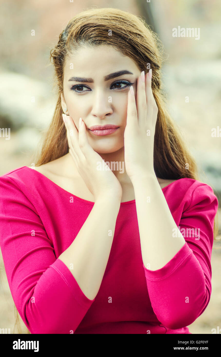 Serious young woman hands on face looking away outdoors Stock Photo - Alamy