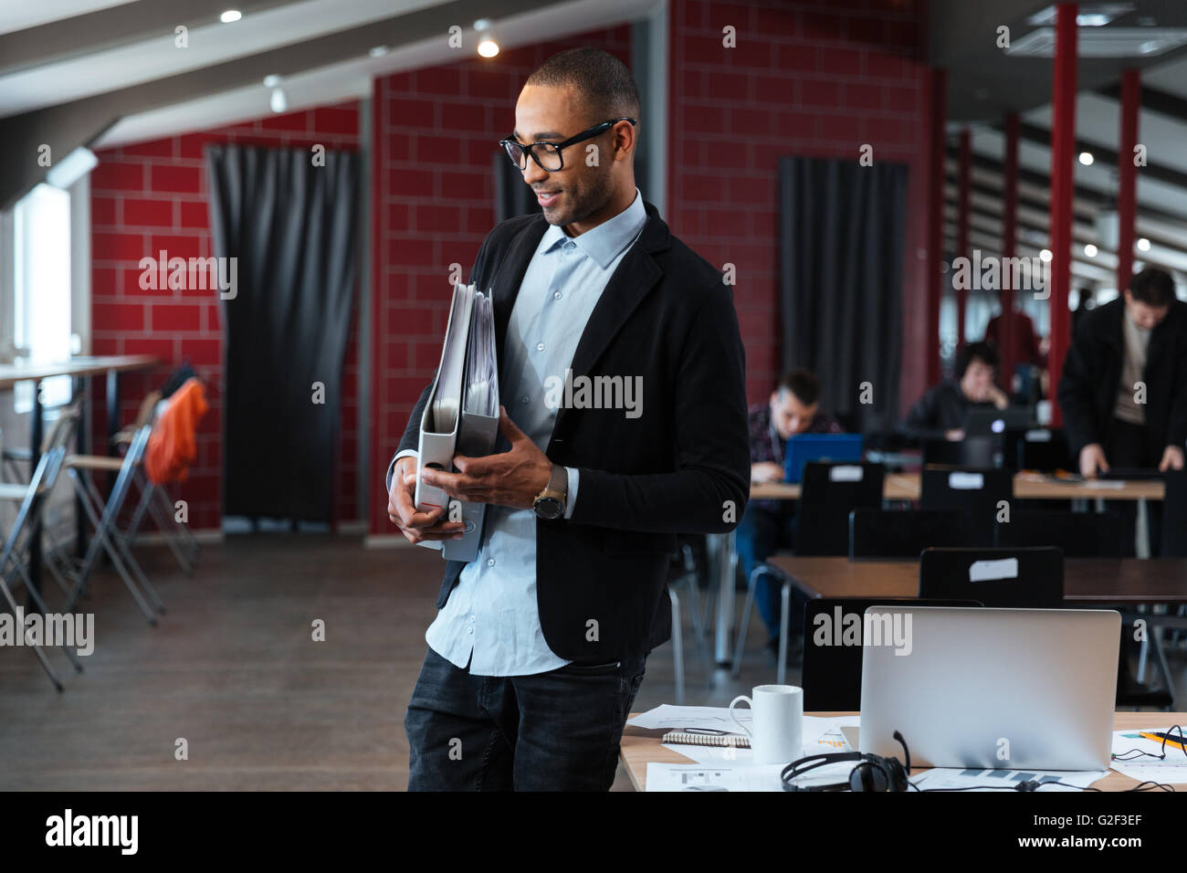 Confident young businessman carrying binders in office Stock Photo - Alamy