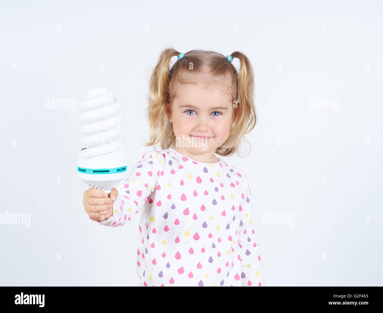 Little girl shows a large energy-saving light bulbs. Ecology Stock ...