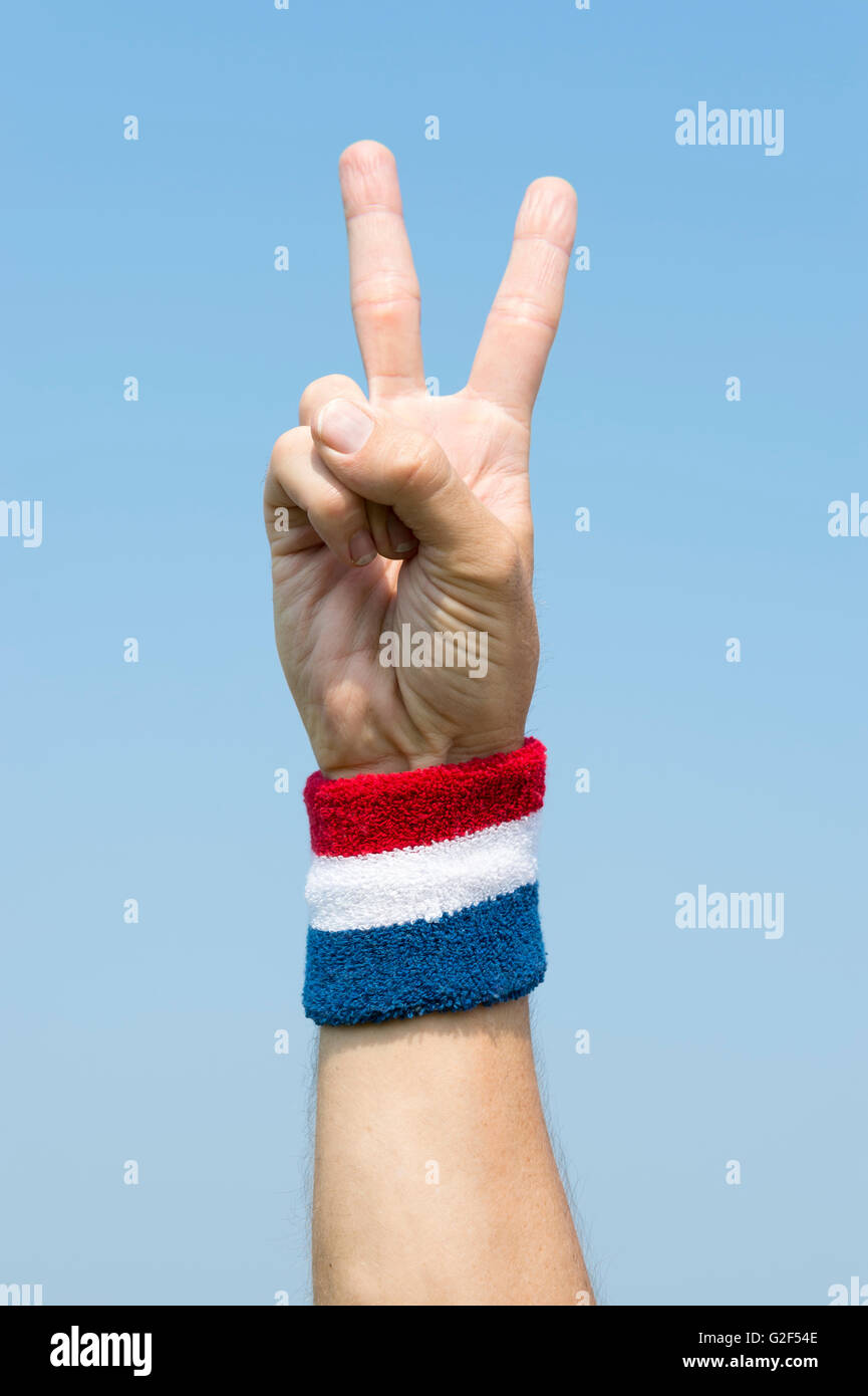 Hand of an athlete making peace sign with finger and thumb against blue ...