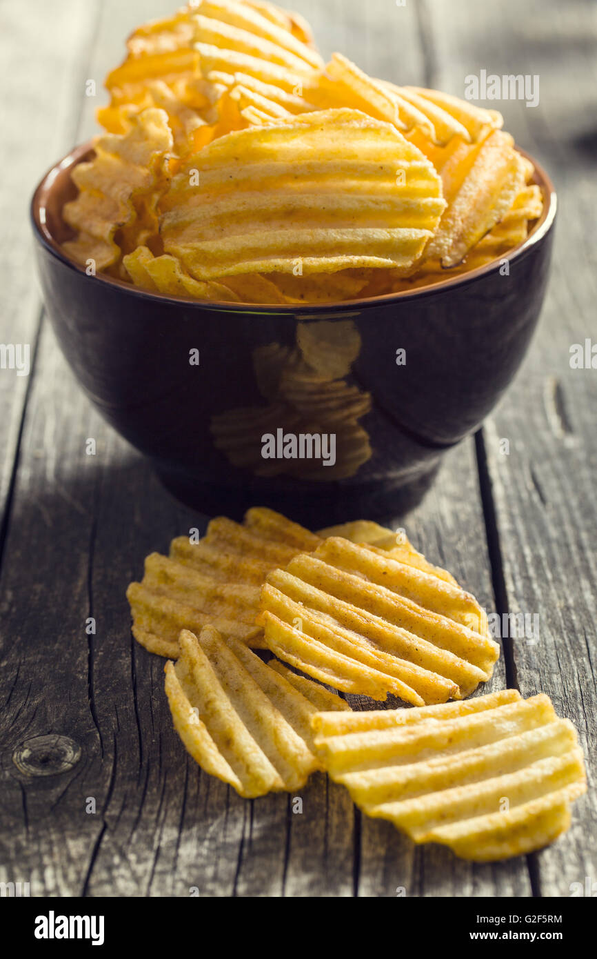 Crinkle cut potato chips on kitchen table. Tasty spicy potato chips in ...