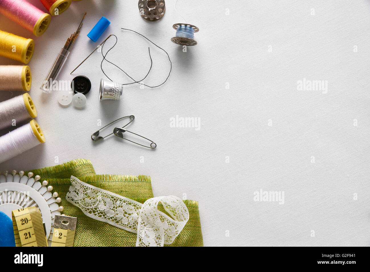 Sewing tools on white fabric background left set. Horizontal ...