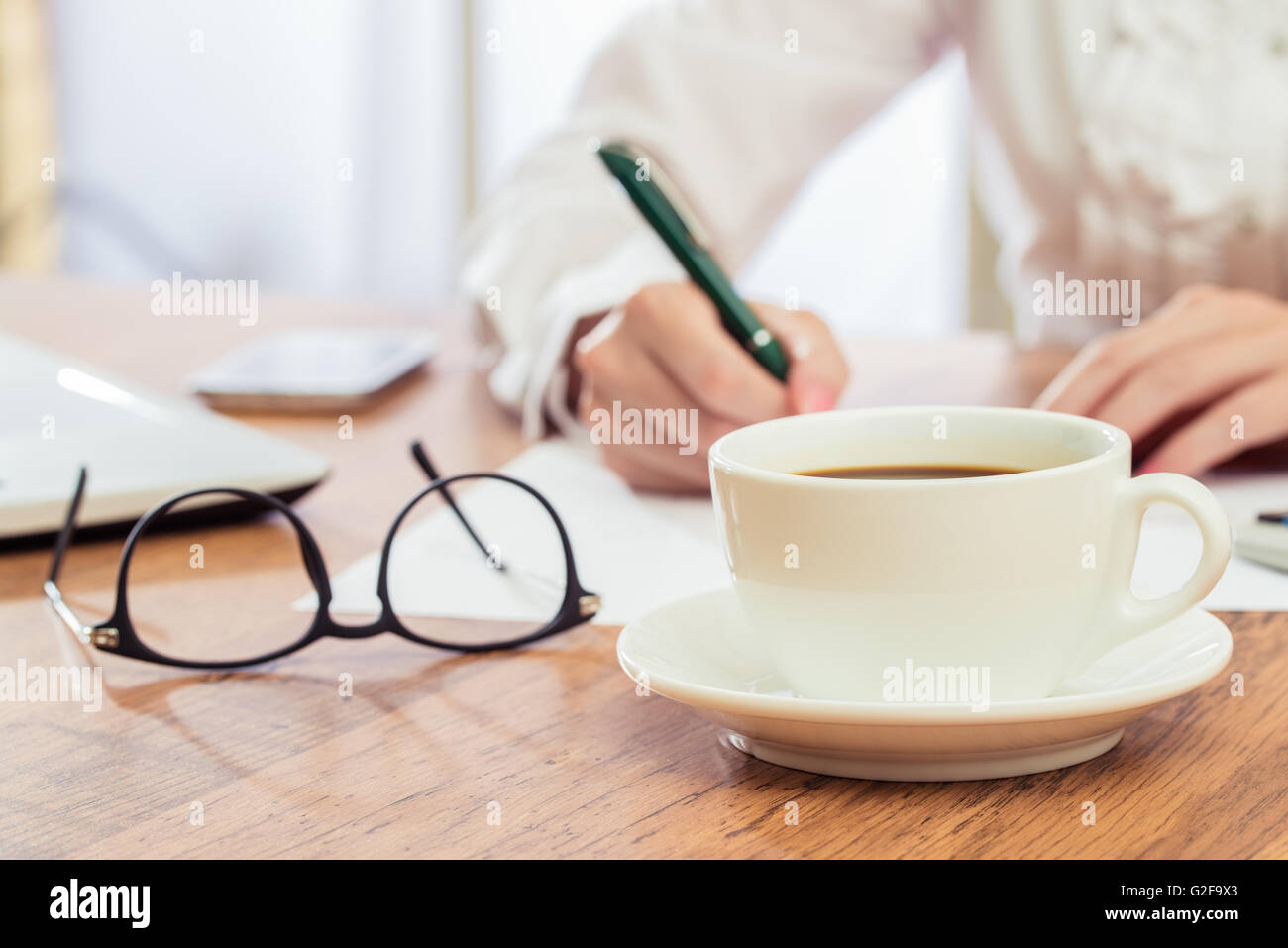 Businesswoman writing and drink coffee at desk, lifestyle Stock Photo ...