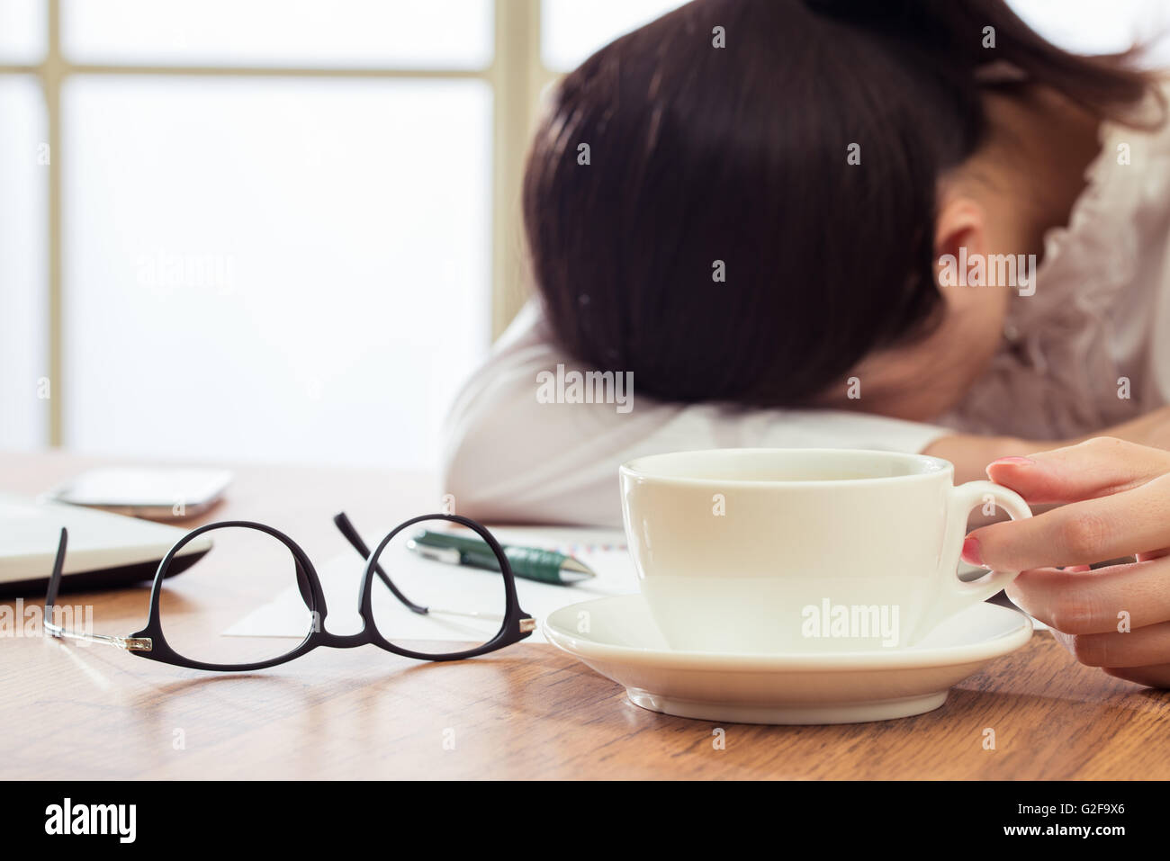 Exhausted and tired young businesswoman holding coffee and sleeping on ...