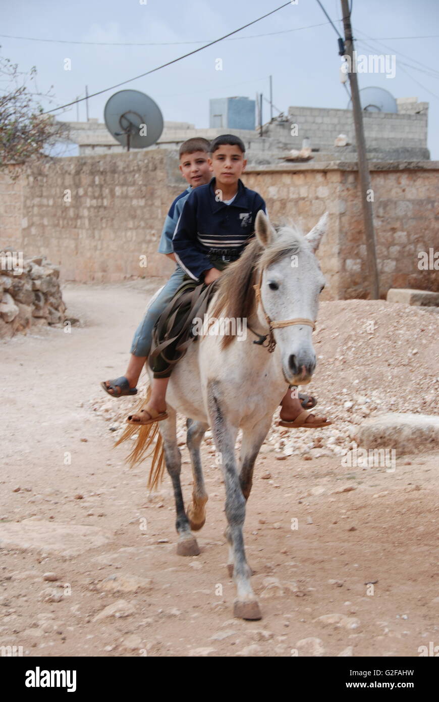 Two Boys Riding Horse Around Qalb Lozeh Stock Photo - Alamy