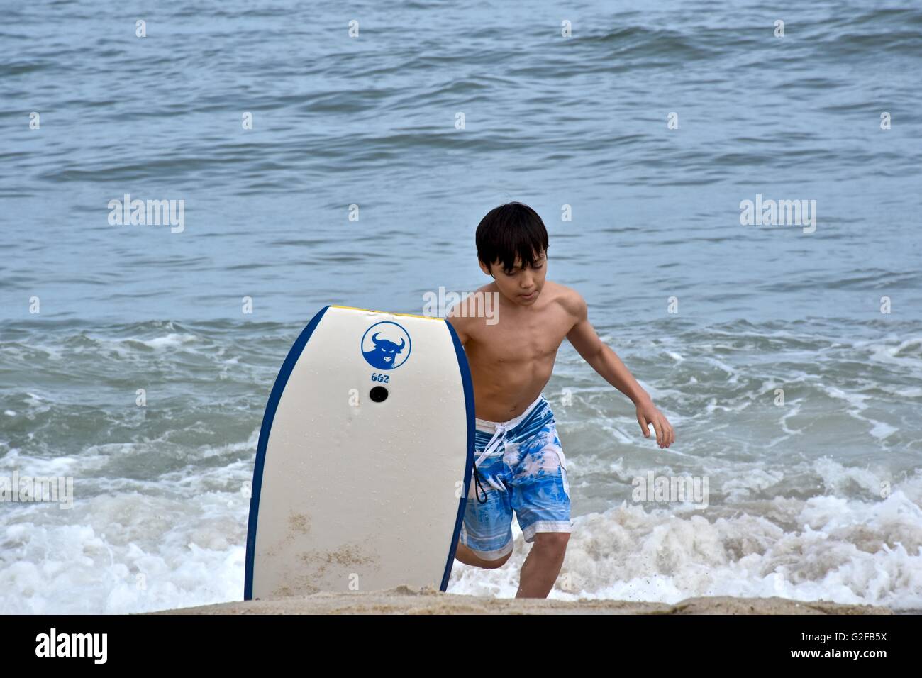A boy boogie boarding while at the beach Stock Photo - Alamy