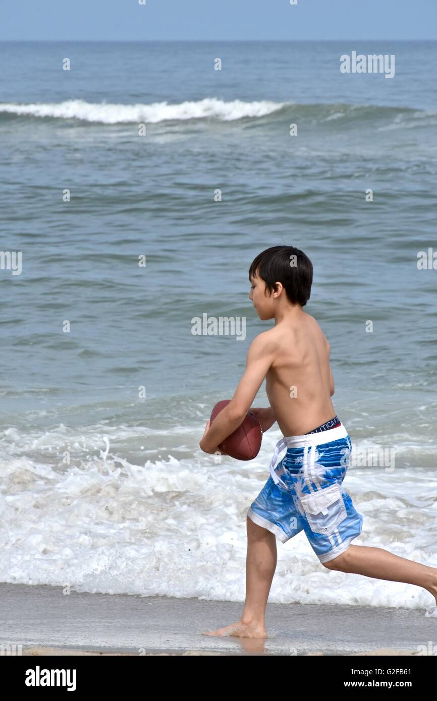 Kid playing football on the beach Stock Photo - Alamy