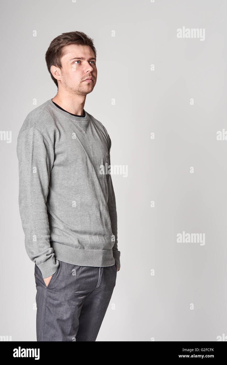 Young man with light beard, hands in pockets, looking out of frame, on ...