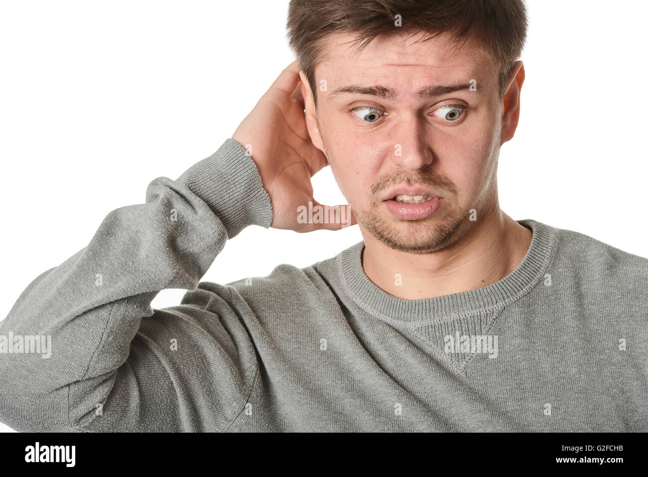 Happy young man with uncertain puzzled expression, on gray Stock Photo ...