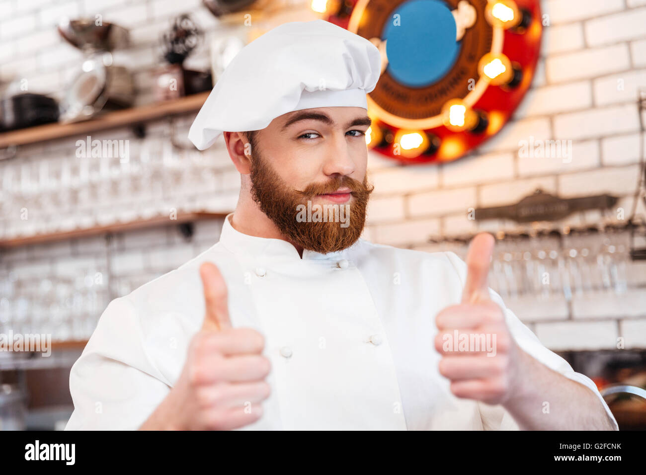 Smiling attractive chef cook showing thumbs up on the kitchen Stock ...