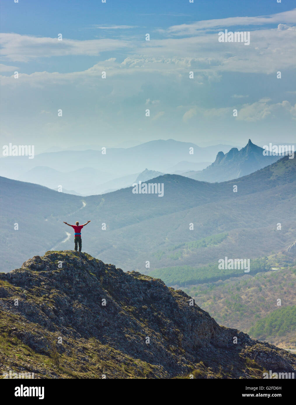 man standing on a cliff in mountains with snowy picks and blue sky with ...
