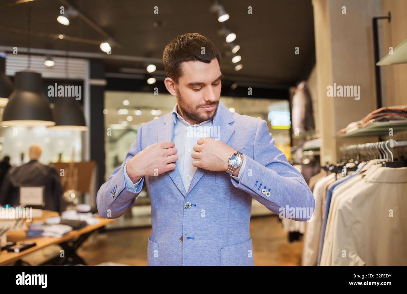 happy young man trying jacket on in clothing store Stock Photo - Alamy
