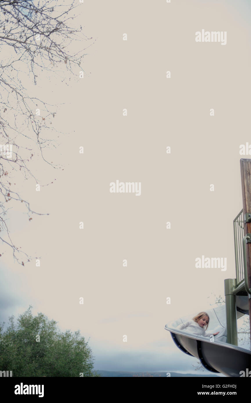 Young Girl Sliding Down Spiral Slide Against Cloudy Sky Stock Photo - Alamy