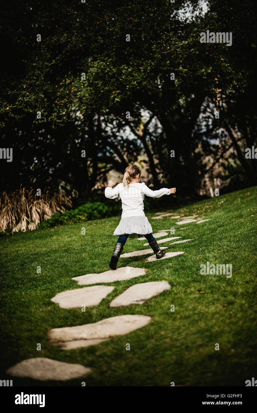 Young Girl Jumping on Stepping Stones, Rear View Stock Photo - Alamy