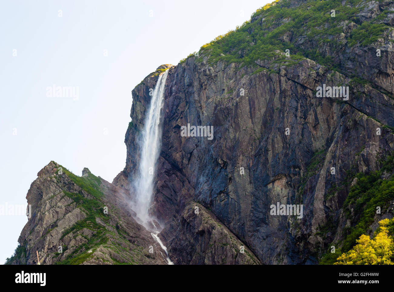 Waterfall flowing and spraying water from top of steep rugged cliffs ...