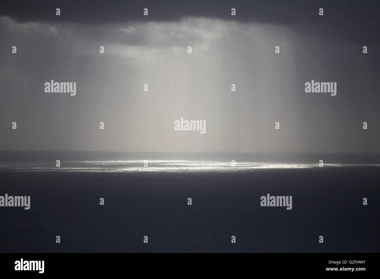 Sun Rays Reflected on Ocean Through Gray Clouds Stock Photo - Alamy